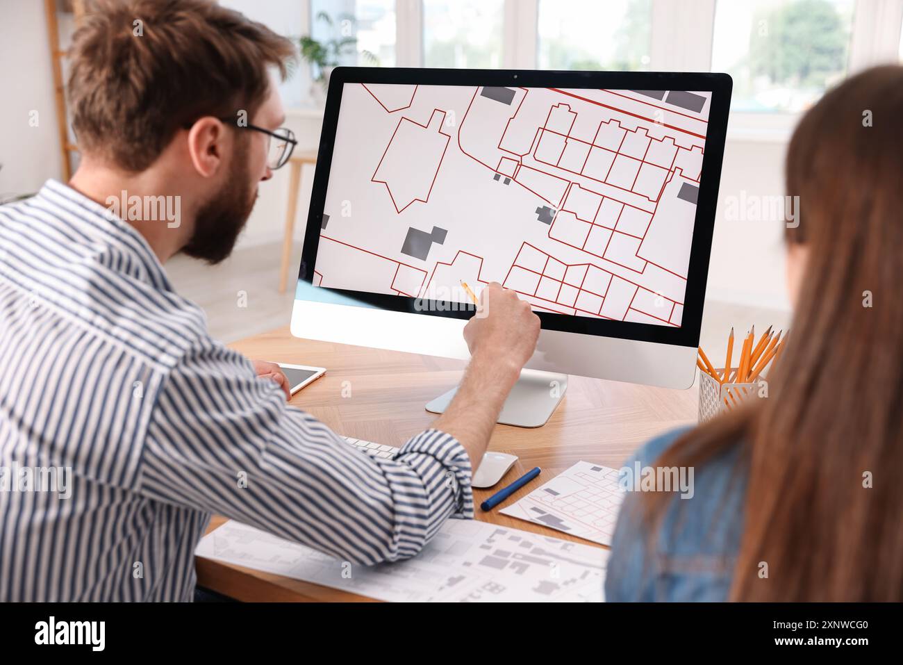 Cartographers working with cadastral map on computer at table in office ...