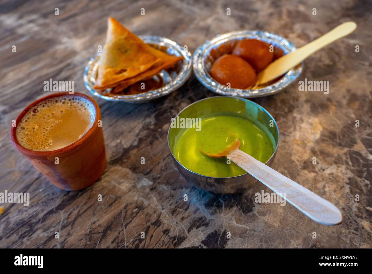 A snack platter featuring samosas, chutney, sweet dessert gulab jamun ...