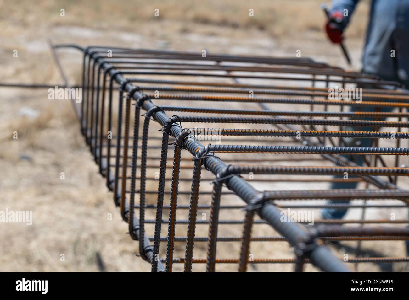 A worker uses steel tying wire to fasten steel rods to reinforcement ...