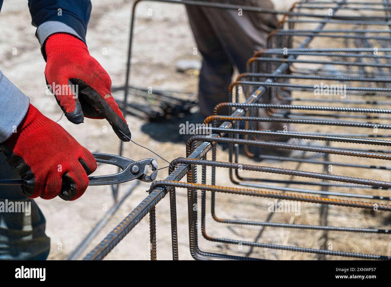 A worker uses steel tying wire to fasten steel rods to reinforcement ...
