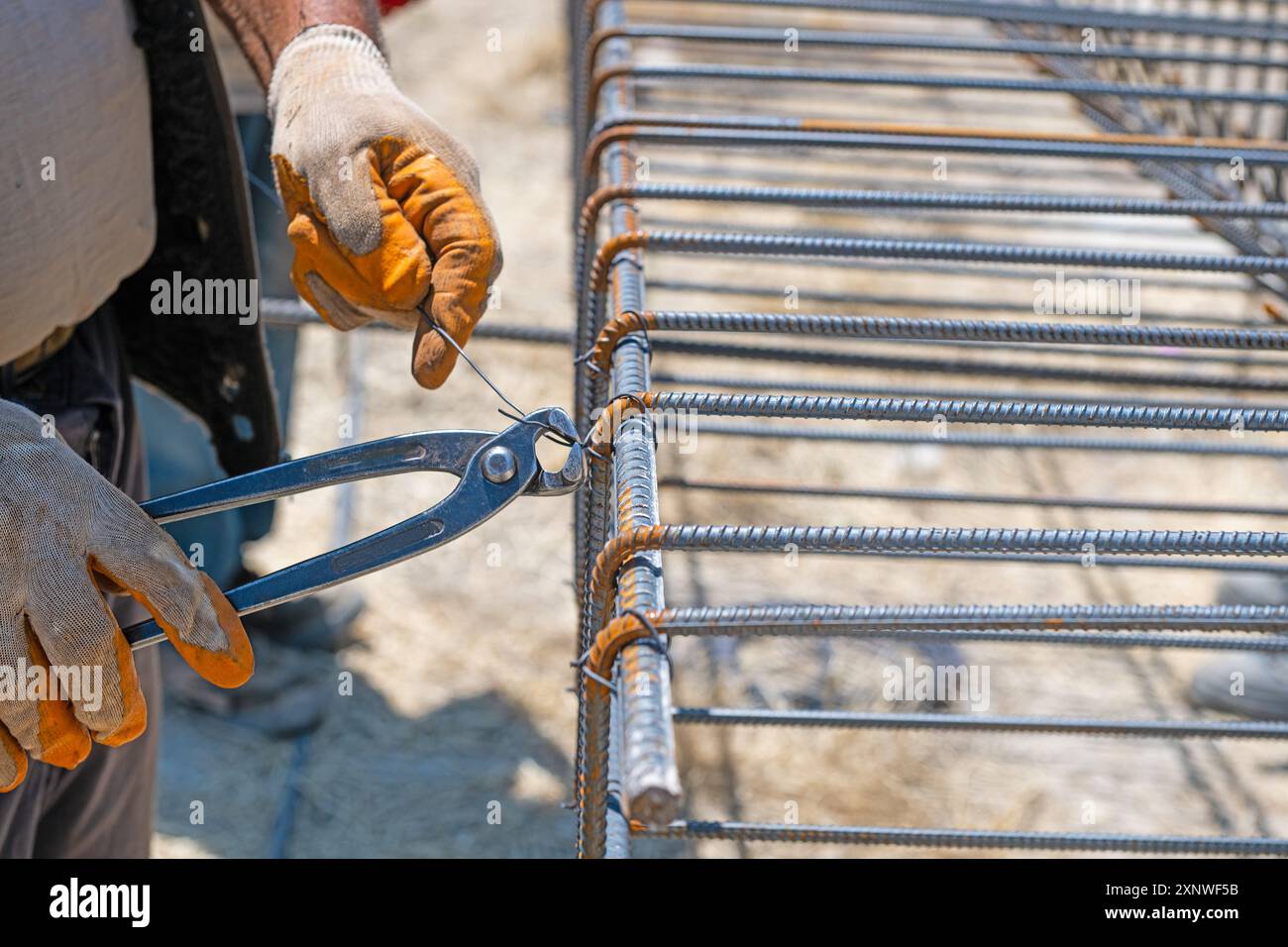 A worker uses steel tying wire to fasten steel rods to reinforcement ...
