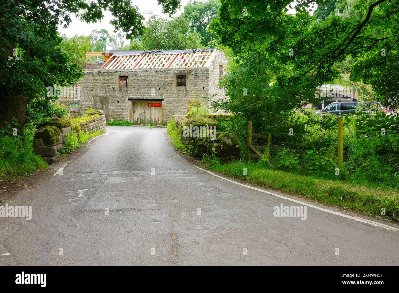 Quaint countryside road leads to an old stone house under renovation ...