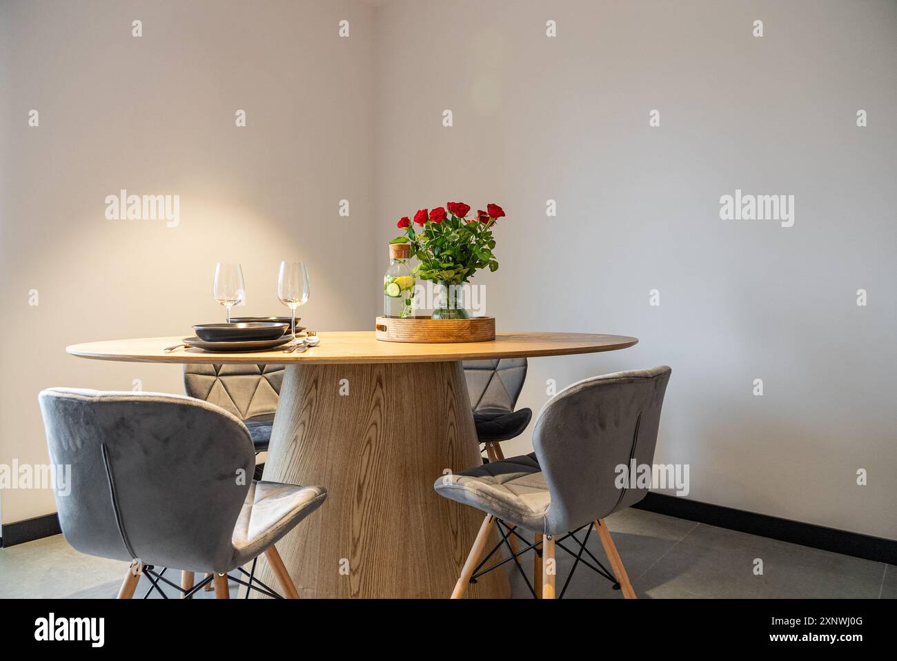Dining table with plates, glasses and vase of red roses. Interior of a ...