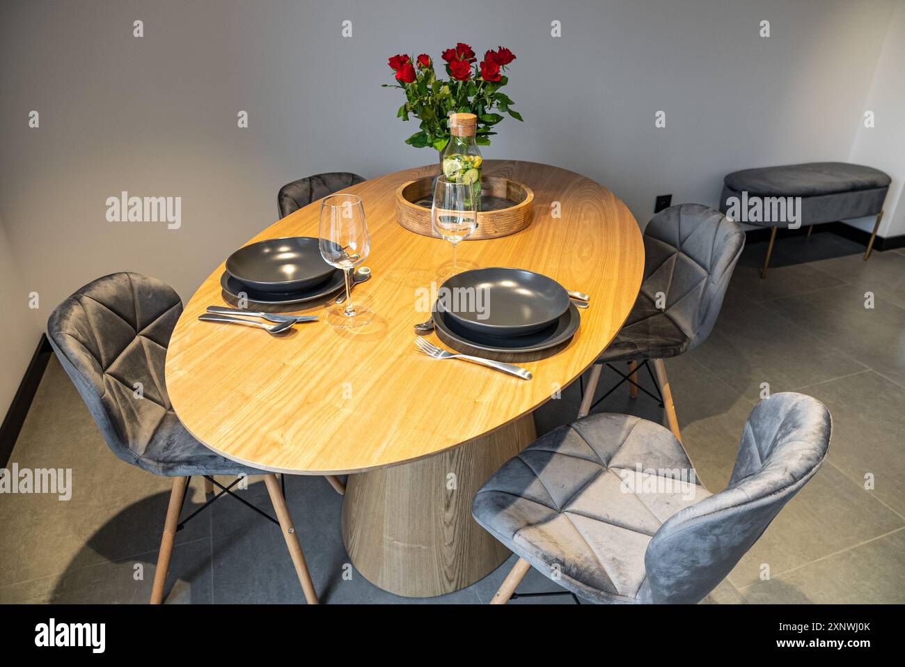 Dining table with plates, glasses and vase of red roses. Interior of a ...