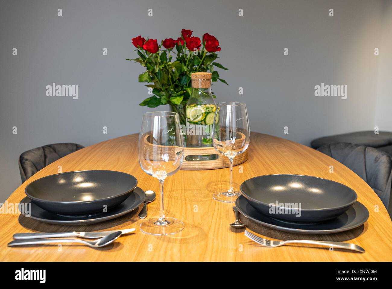 Dining table with plates, glasses and vase of red roses. Interior of a ...