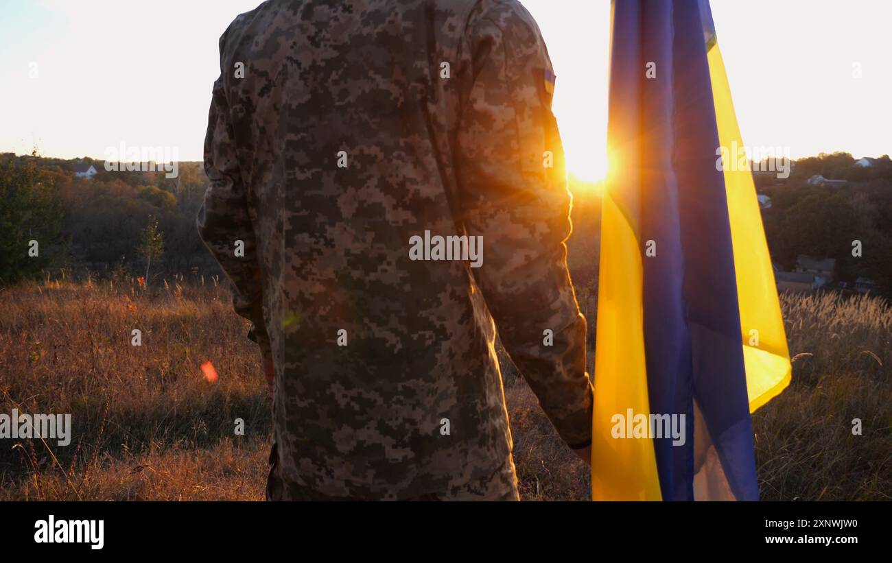 Male ukrainian army soldier stands with national banner against ...