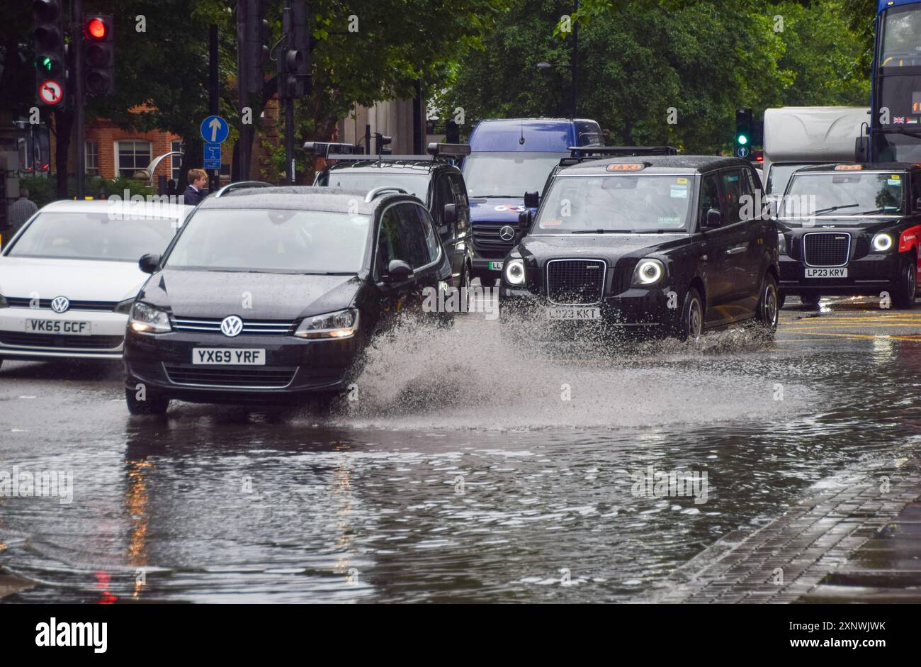 London, UK. 9th July 2024. Cars splash through a waterlogged Euston ...