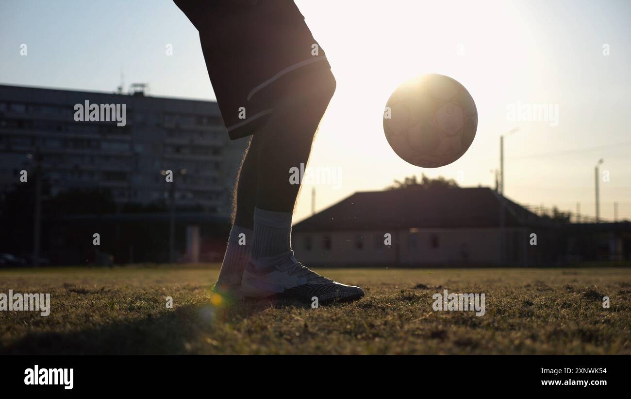 Legs of young man kicking ball at green field. Male feet of ...