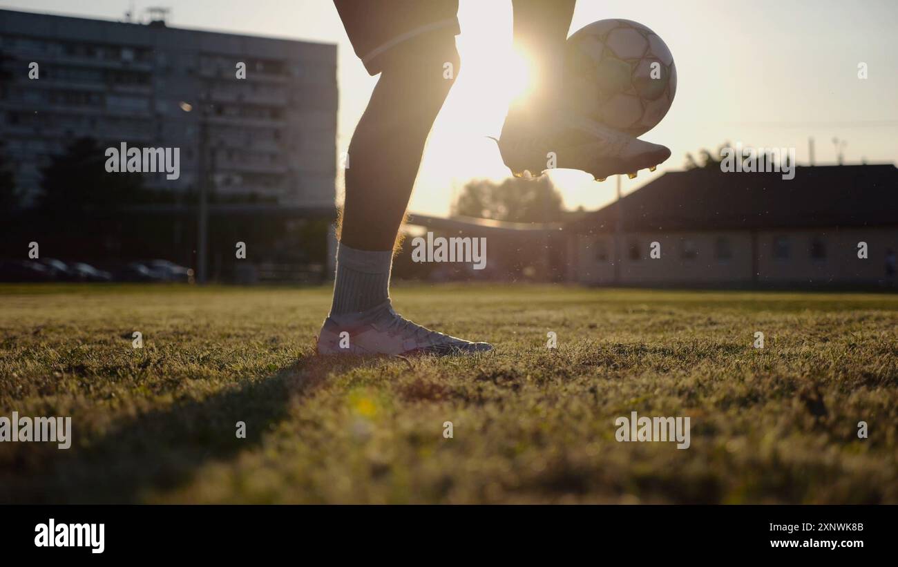 Legs of young man kicking ball at green field. Male feet of ...