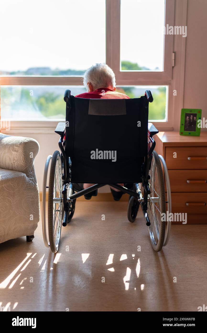 Elderly woman with white hair sitting in a wheelchair and looking ...