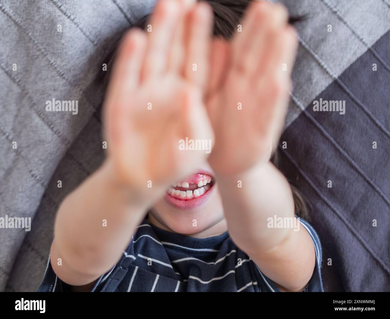 Little boy covers his face with hands. Child refuses to be photographed ...