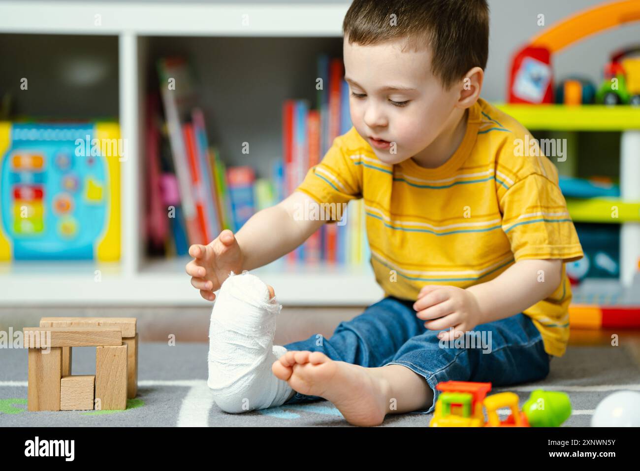A little toddler boy holds his leg in a cast with his hands. Fracture ...