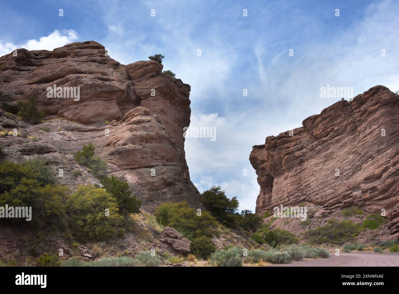 Dirt road curves around giant, red sandstone cliffs in San Lorenzo ...
