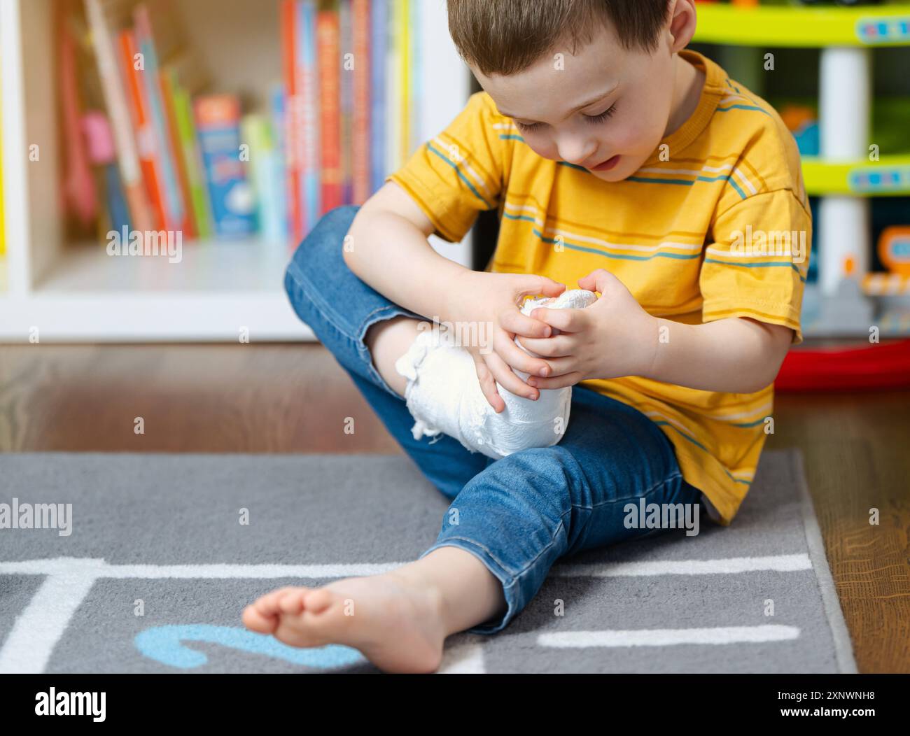 A little toddler boy holds his leg in a cast with his hands. Fracture ...