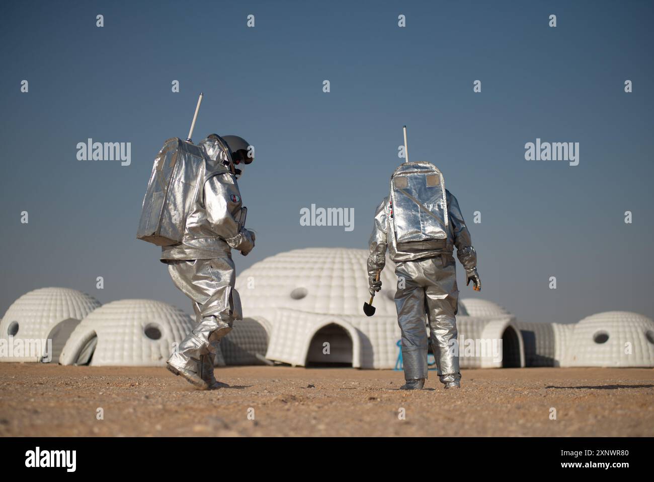 Two astronauts in silver suits conducting a Mars mission simulation in ...