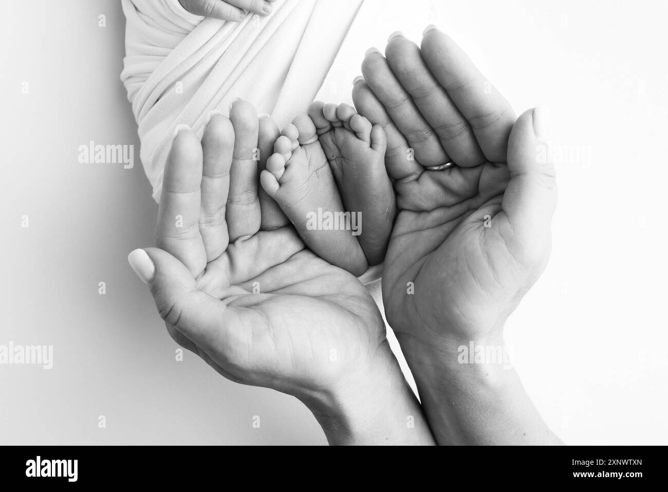 The palms of the father, the mother are holding the foot of the newborn ...