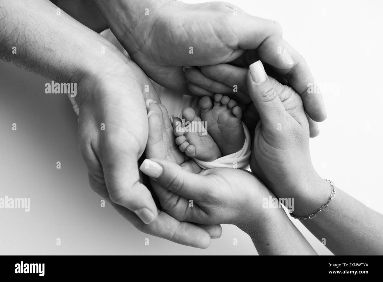 The palms of the father, the mother are holding the foot of the newborn ...