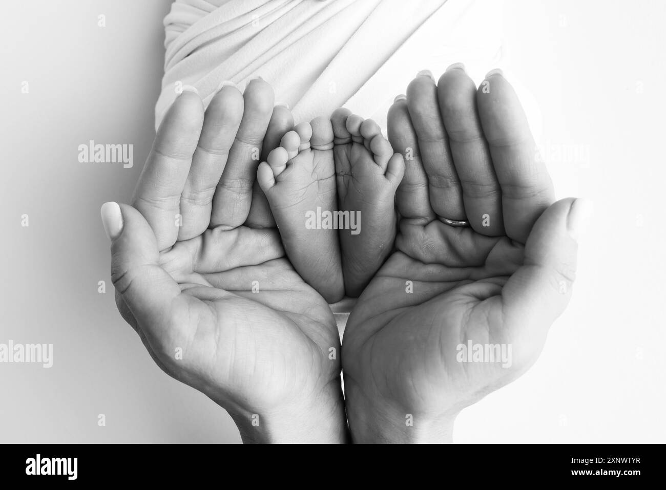 The palms of the father, the mother are holding the foot of the newborn ...