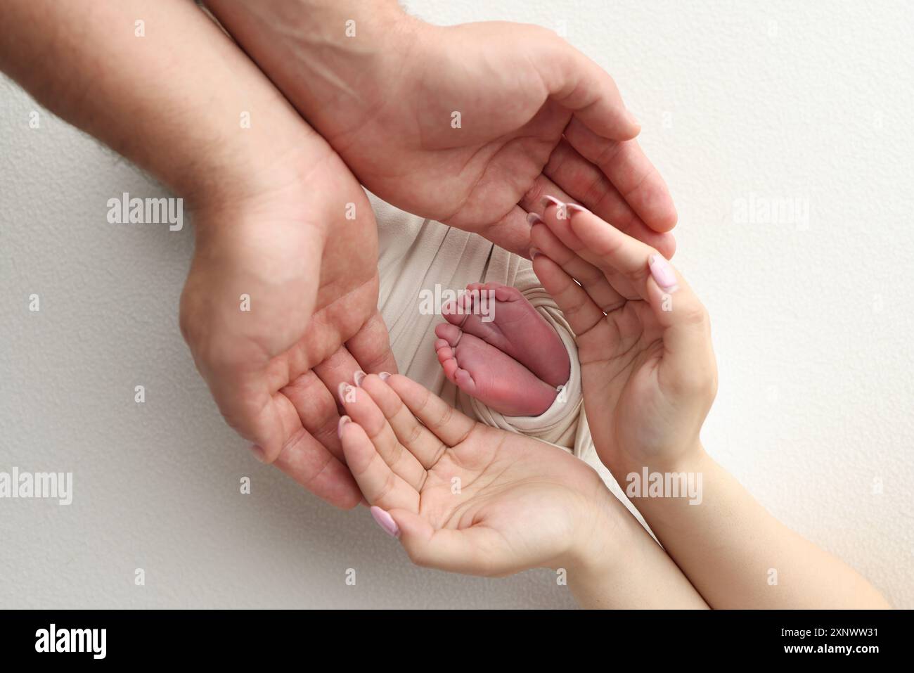 The palms of the father, the mother are holding the foot of the newborn ...
