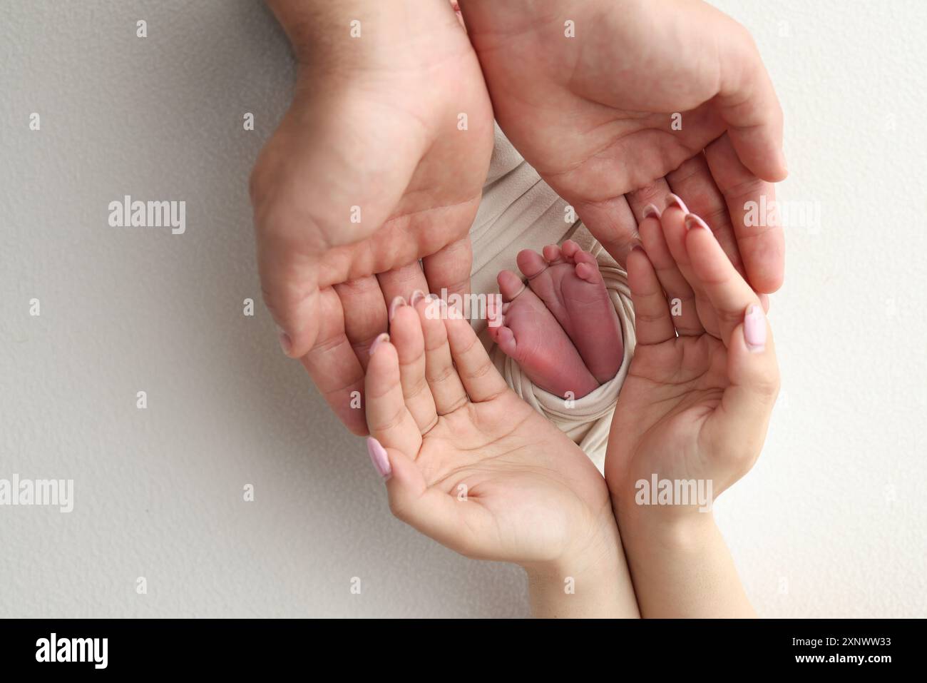 The palms of the father, the mother are holding the foot of the newborn ...