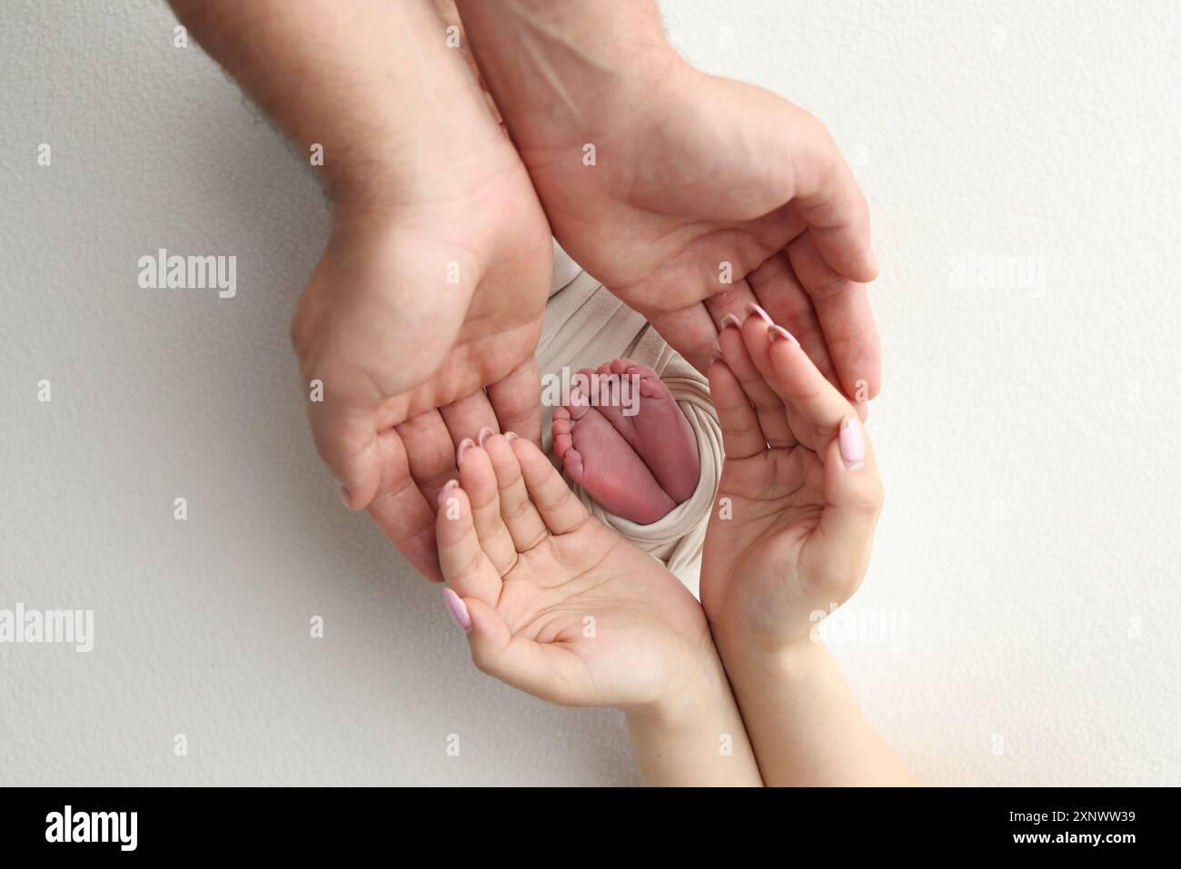 The palms of the father, the mother are holding the foot of the newborn ...