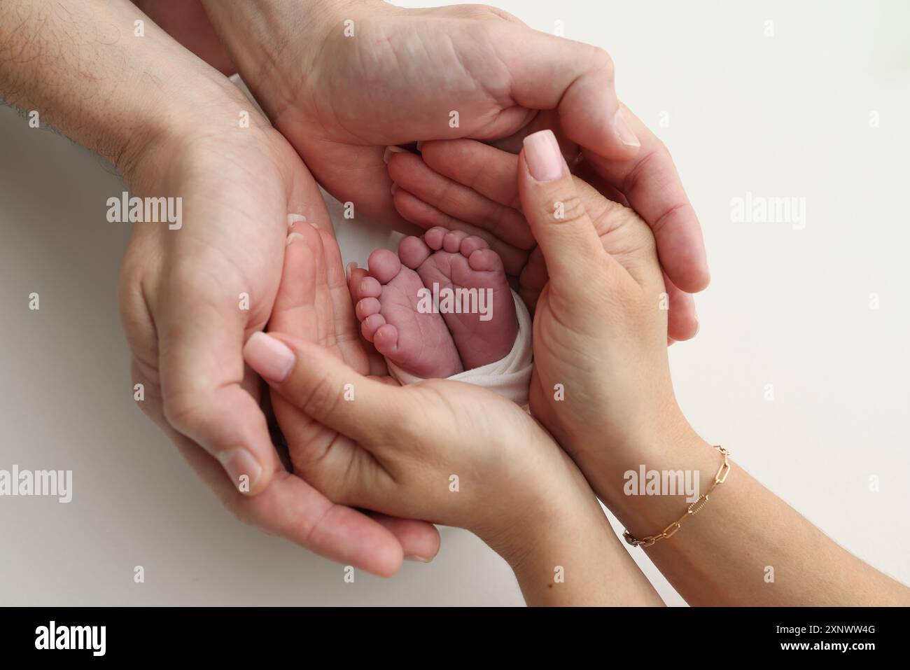 The palms of the father, the mother are holding the foot of the newborn ...