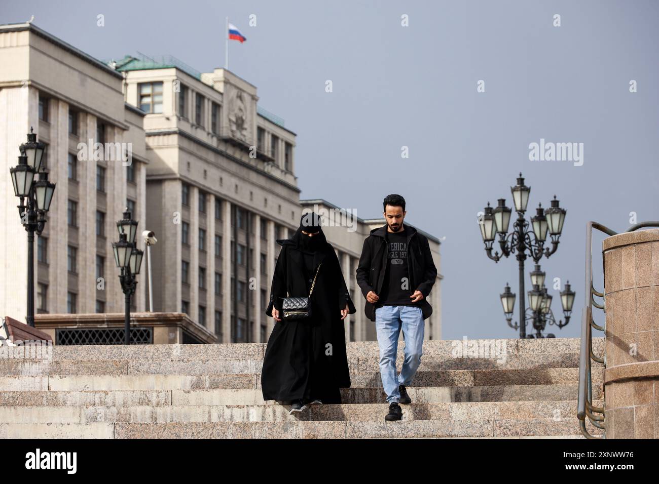 Muslim woman wearing abaya and niqab and man walking on background of ...