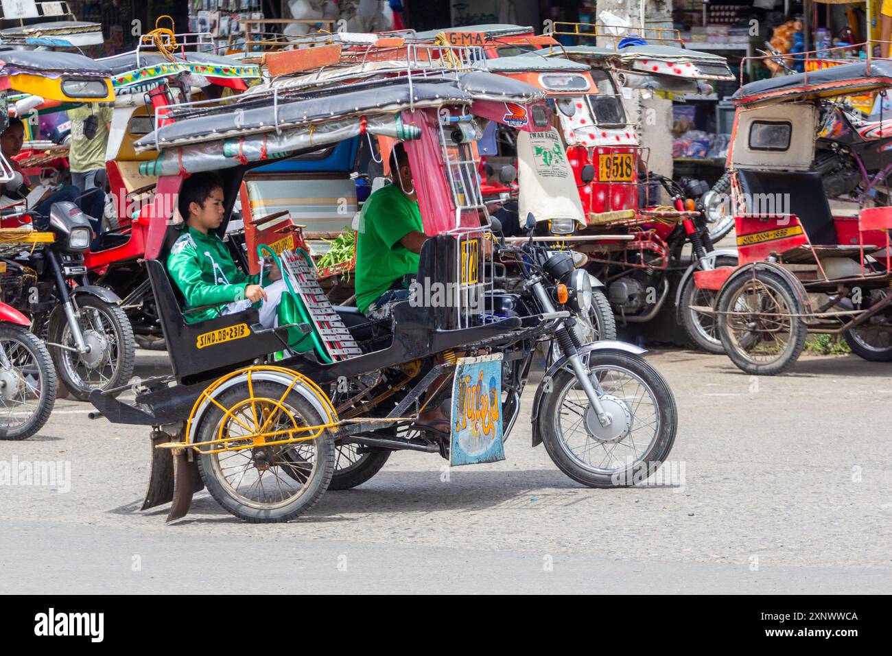 Passengers riding a tricycle, a popular public transport in the ...