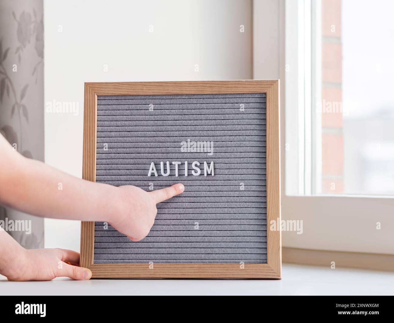 Kid points on grey letterboard with word Autism. Medical diagnosis ...