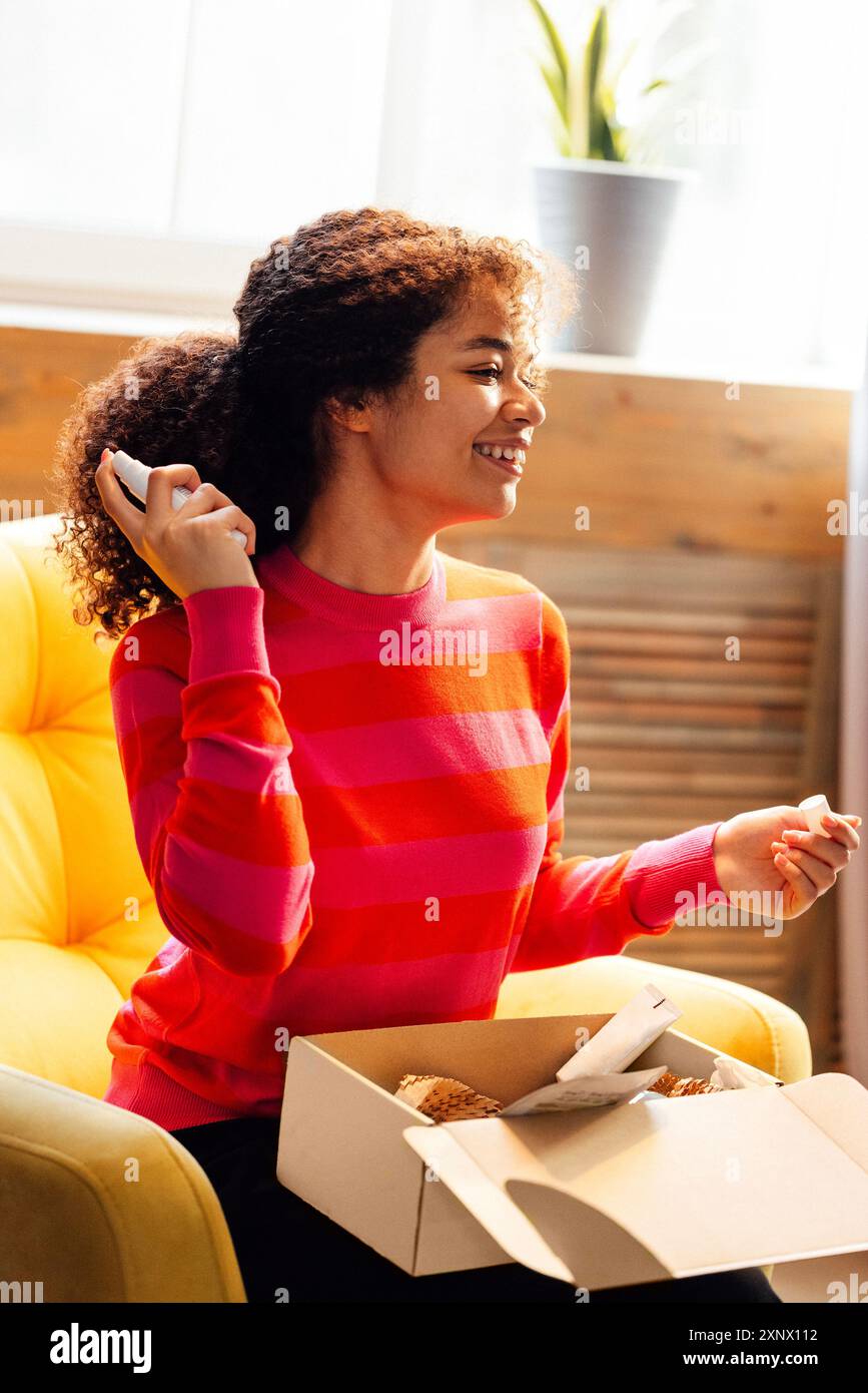 A young African woman unpacks a cardboard box with beauty products. A ...