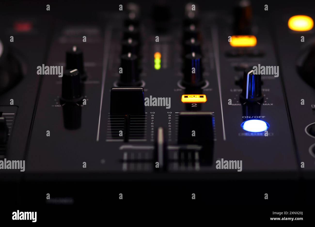 A close-up view of an audio mixer with various knobs, buttons, and ...