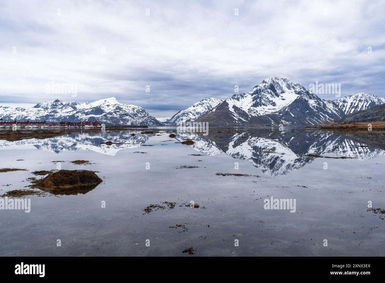 Tall mountains with snowy peaks reflecting in the calm water of the ...