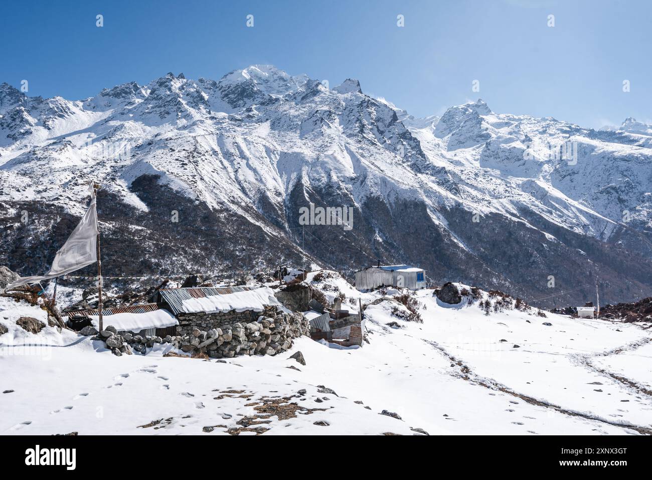 Stone walls in the snows and snowy mountain range, Kyanjin Gompa, Langtang Valley trek ...