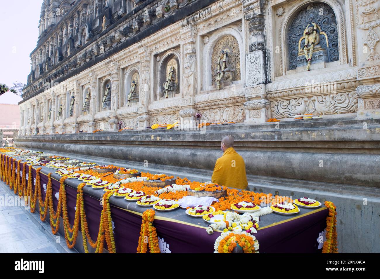 Flower offerings and a monk at the Buddhist Mahabodhi Mahabihara Temple ...