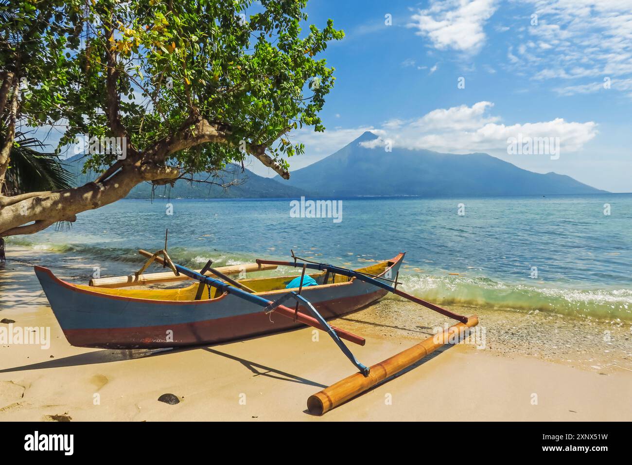 Outrigger canoe moored on Kalea Beach with active Karangetang volcano ...