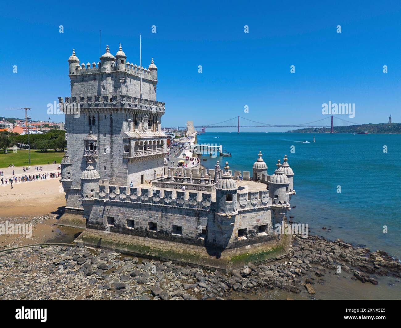 A historic tower on the waterfront with a bridge in the background and ...