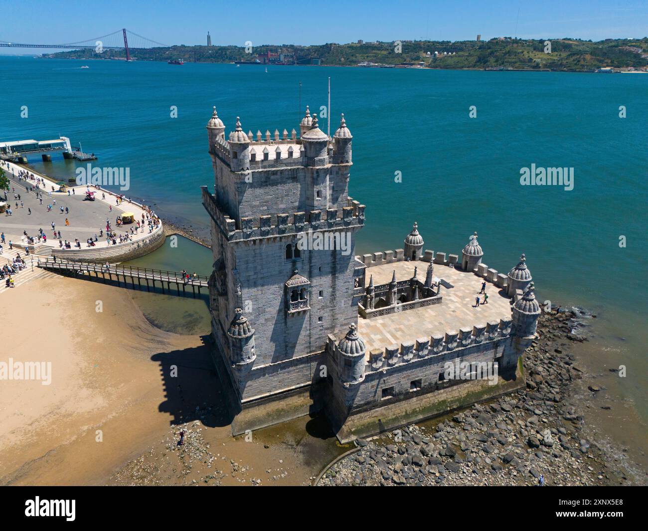 A historic tower on a rocky shore with blue water and sky in the ...