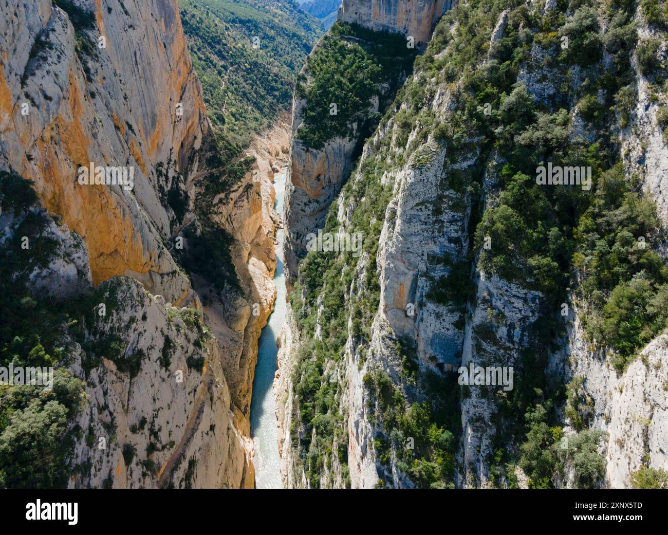 A river flows through a deep, narrow gorge with high, wooded rock faces ...