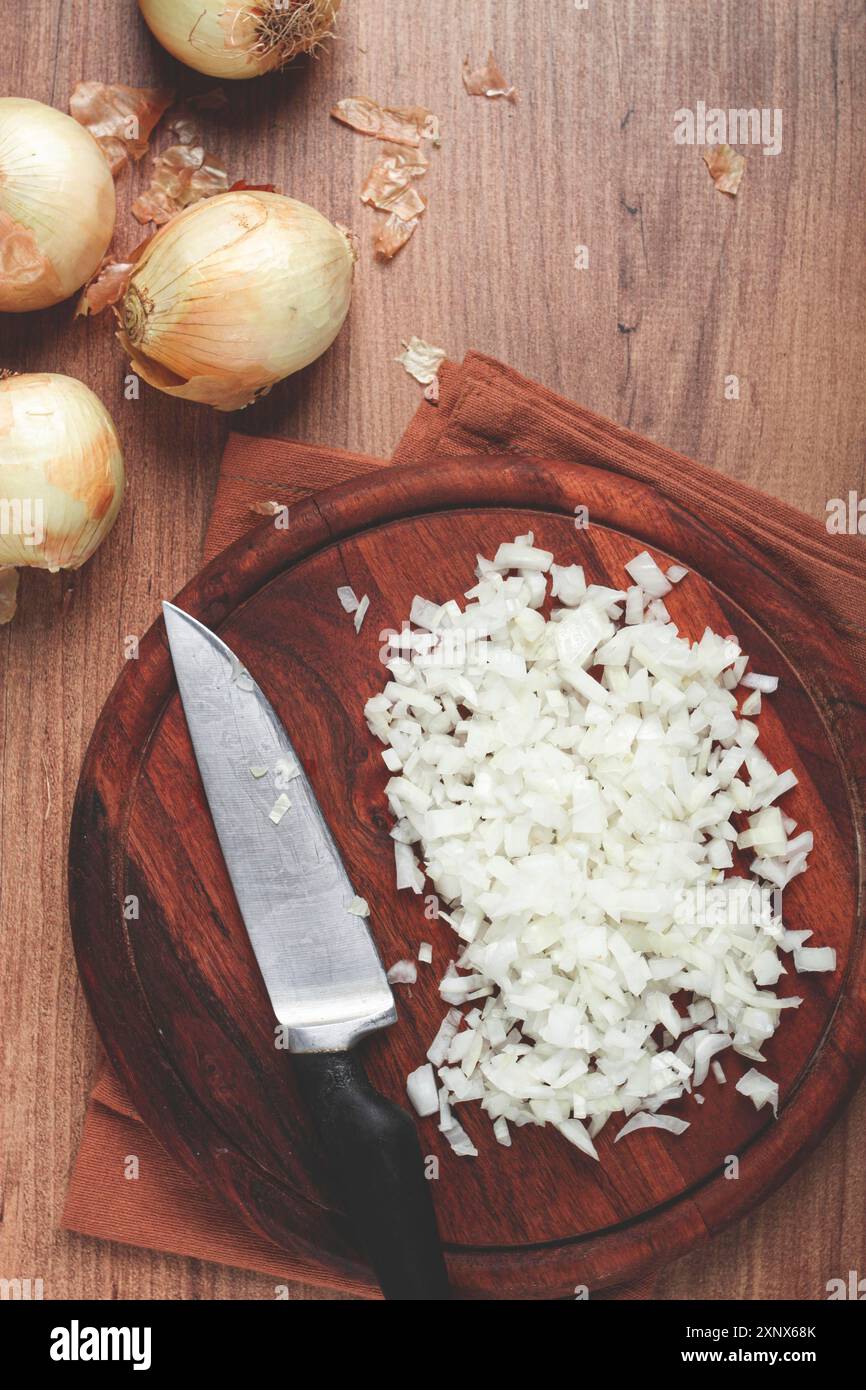Finely chopped onion on a chopping board with a knife, wooden table ...