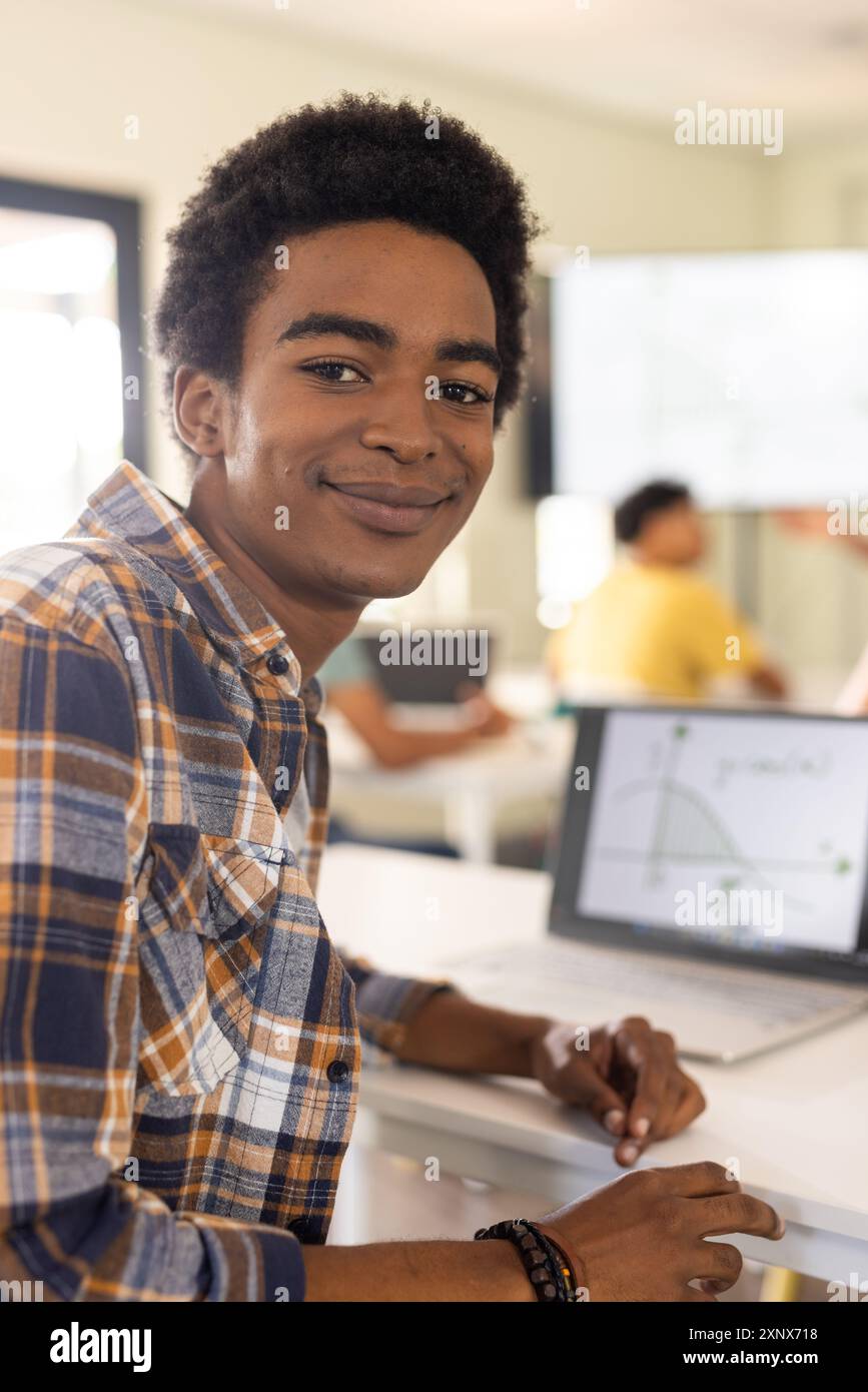 In high school, teenage boy smiling and using laptop in classroom ... In high school, teenage boy smiling and using laptop in classroom ...