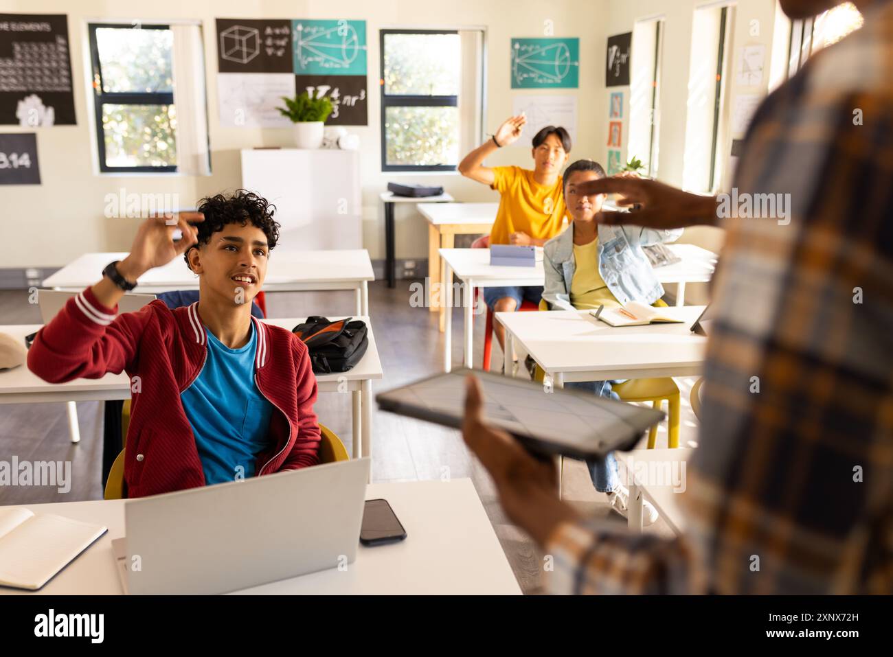 In high school, students raising hands to answer teacher's question in ...