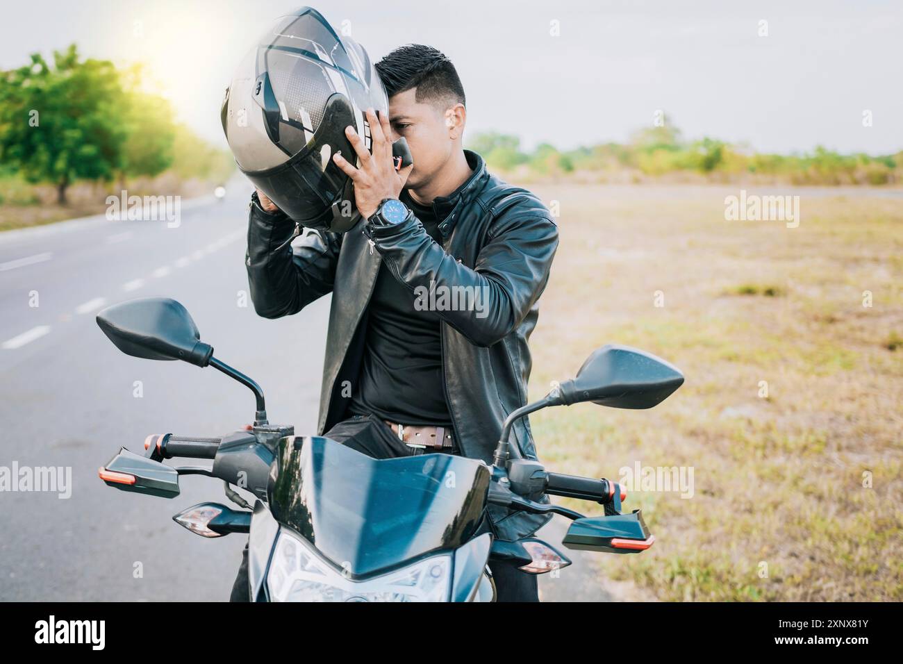 Male biker on motorcycle putting on safety helmet. Biker motorcycle ...