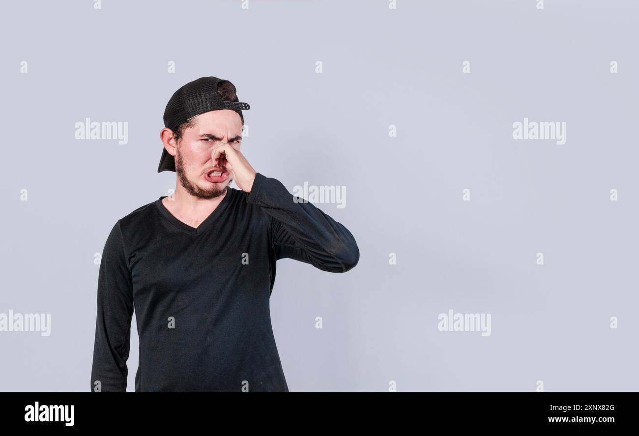 Young man covering nose isolated. Guy with a face of unpleasant odors ...
