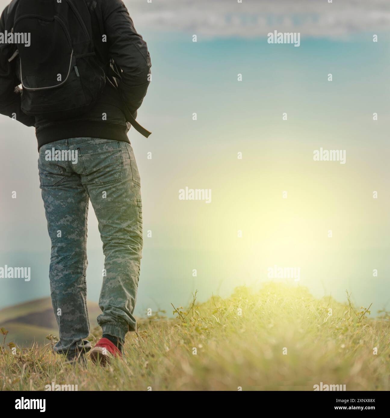 Low angle of backpacker man walking in the countryside. Rear view of ...