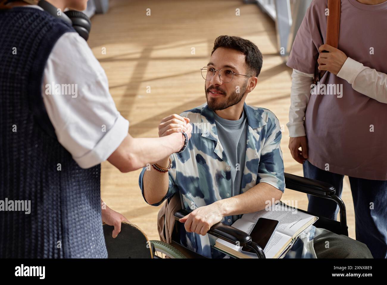 Portrait shot of cheerful Middle Eastern male student using wheelchair ...
