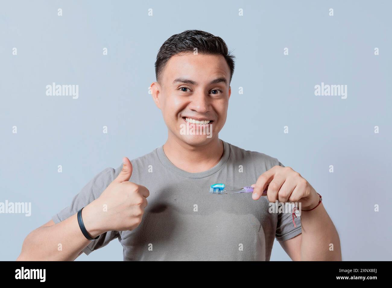 Smiling handsome guy holding a toothbrush with thumb up. Smiling people ...