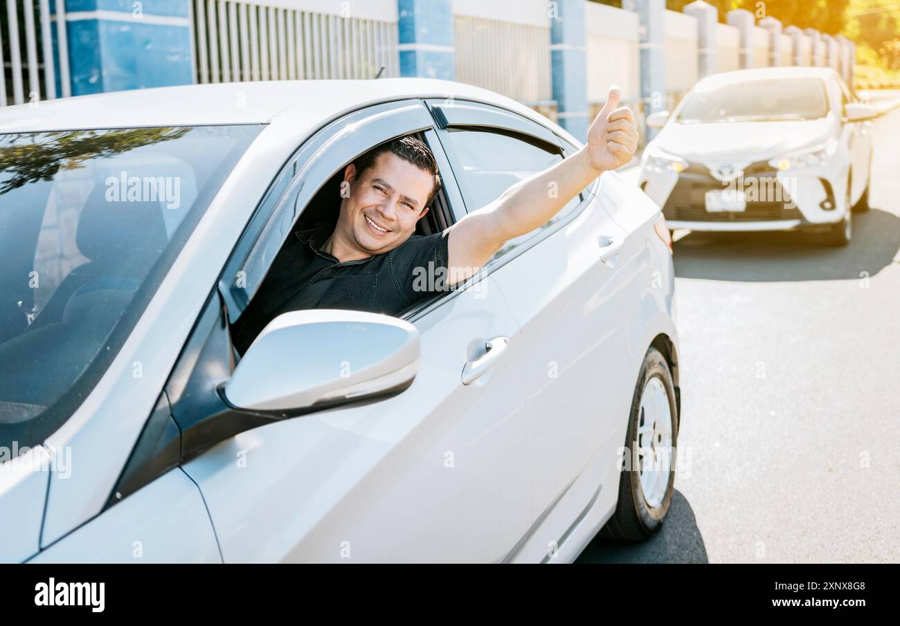 Smiling driver giving a thumbs up on the road. Satisfied driver man ...