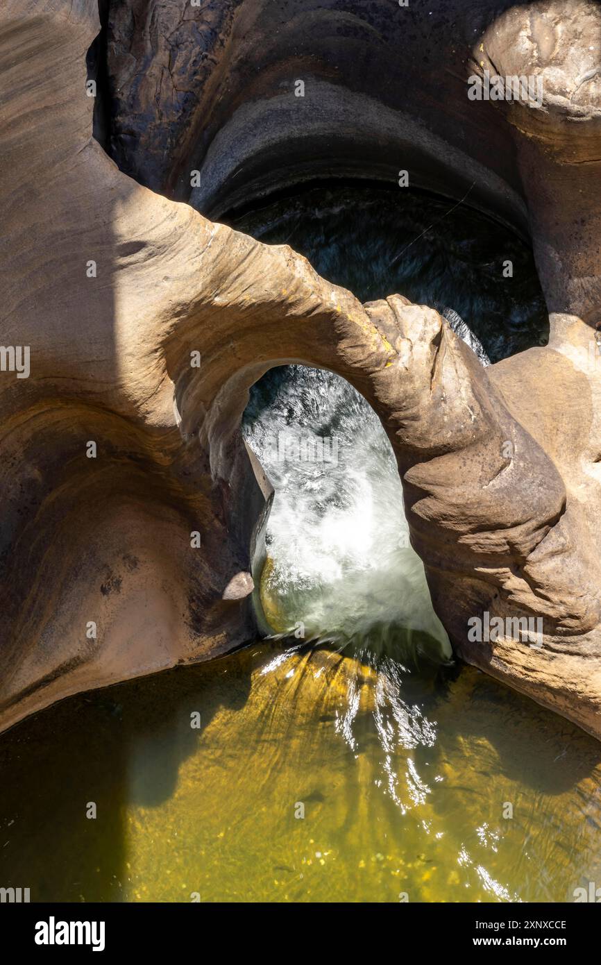 Water flowing through eroded rock formations, canyon with steep orange ...