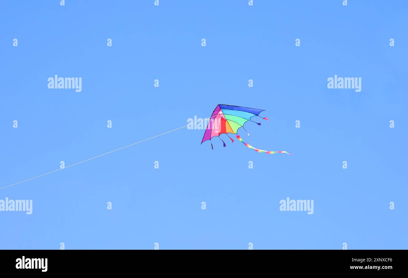 kite with rainbow colors flying in the blue sky tied to a string Stock ...