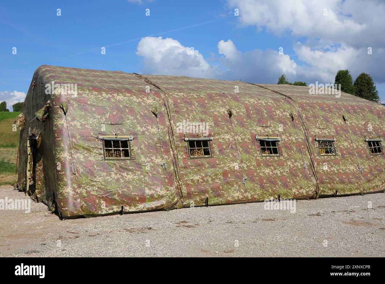 camouflaged military tent set up in a training camp during wartime with ...